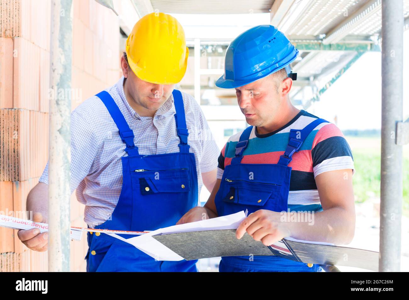 Construction Team with building plans on site Stock Photo - Alamy