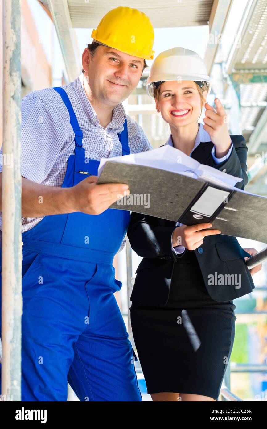 Team or architect and builder or worker with helmets controlling or ...