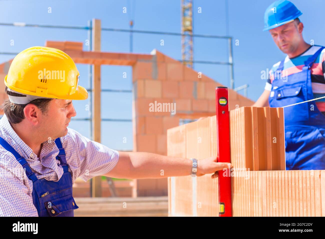 Construction site workers or bricklayer with helmets controlling ...