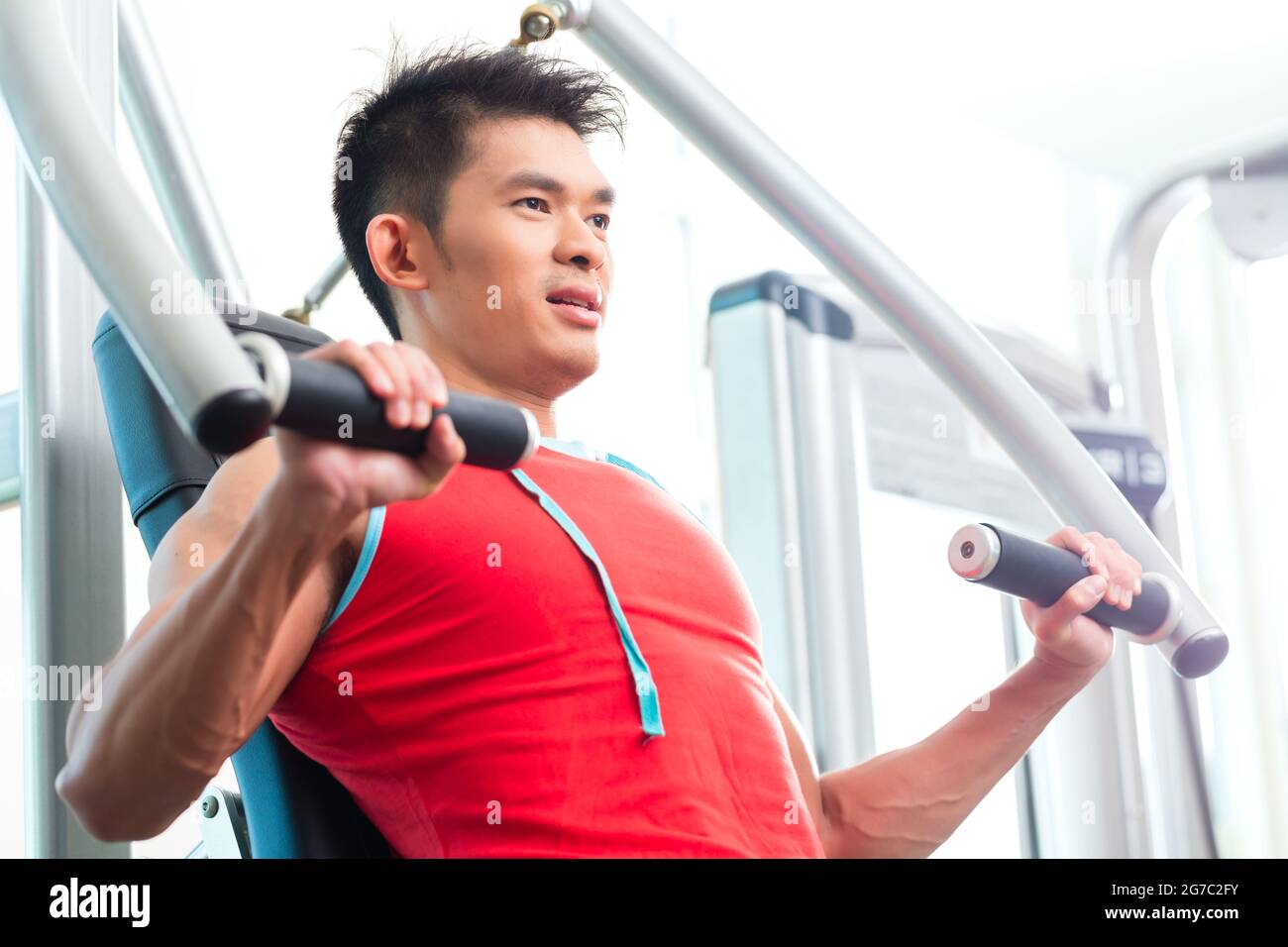 Asian Chinese man having fitness training or workout in gym doing sport ...