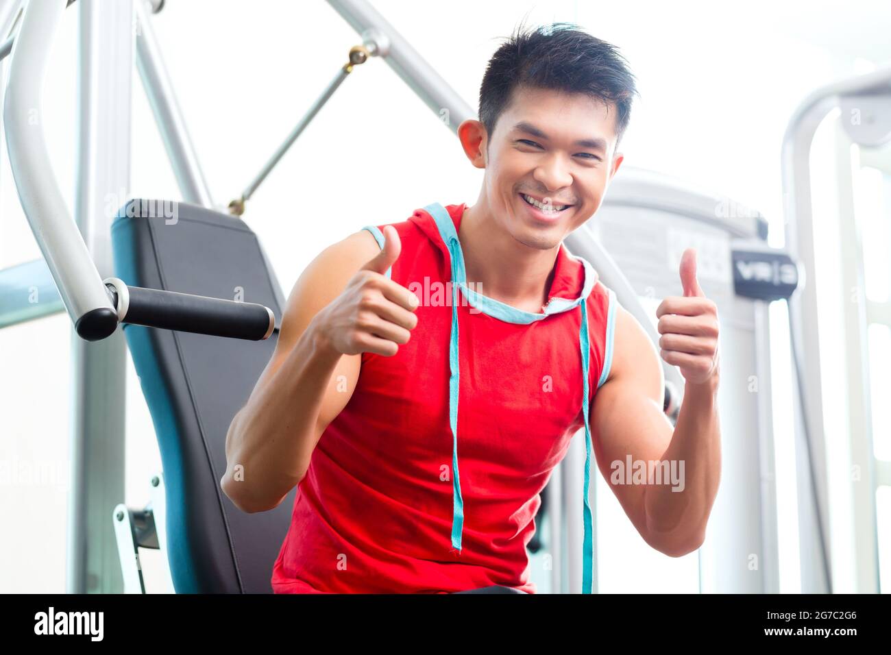 Asian Chinese man having fitness training or workout in gym doing sport ...