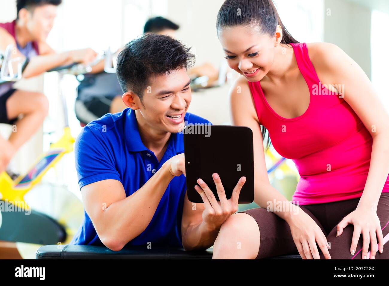 Asian Chinese Woman and personal fitness trainer in gym discussing ...