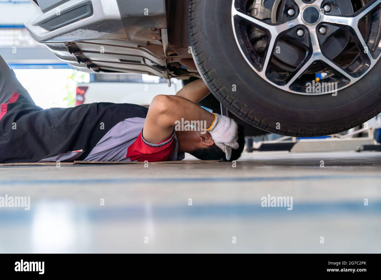 car mechanic adjusting tension in vehicle suspension Element at auto ...