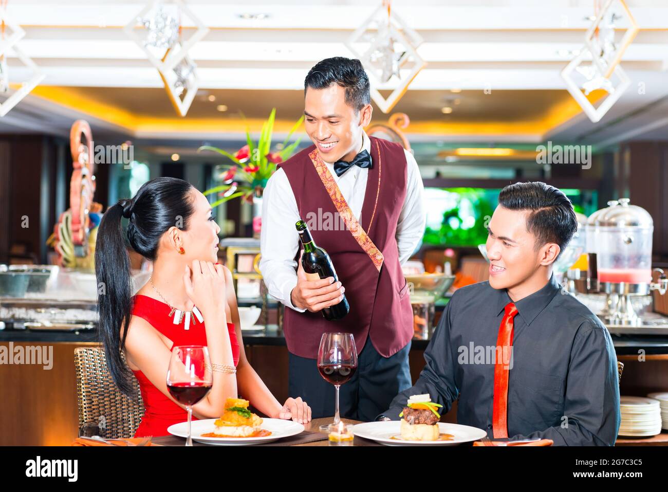 Waiter serving wine in Asian restaurant Stock Photo - Alamy