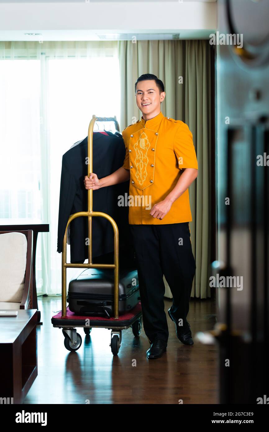 Portrait of bell boy pulling box van in Asian hotel Stock Photo - Alamy