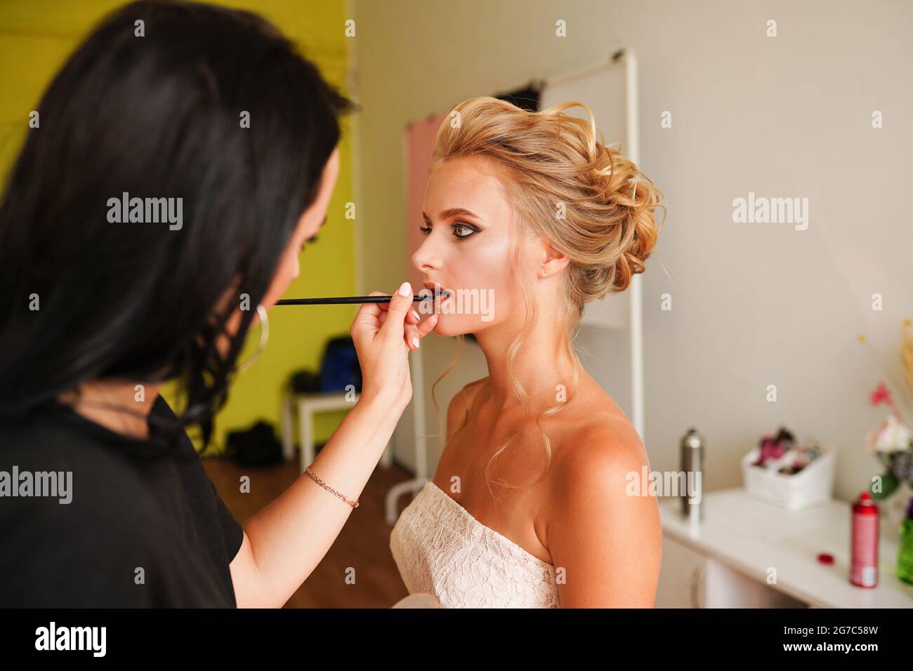 Professional female makeup artist applying cosmetics on model face use ...