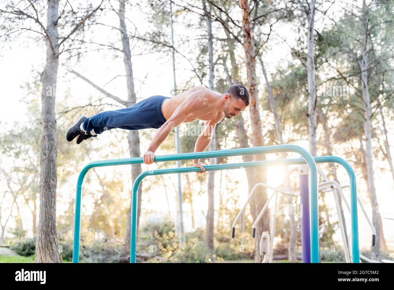 Side view of a male athlete exercising on parallel bars Stock Photo - Alamy