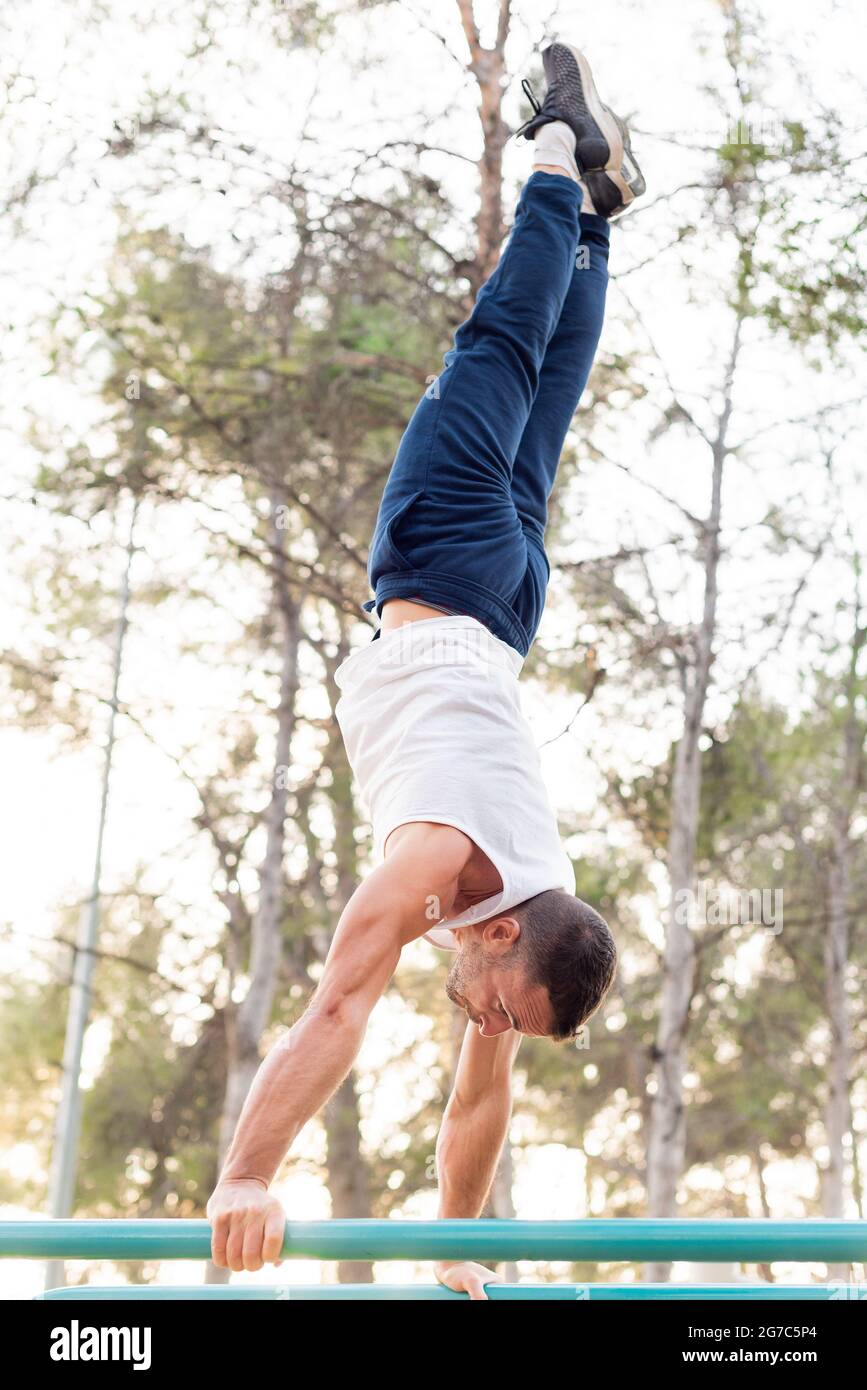 Man doing handstand on bars in the park Stock Photo - Alamy
