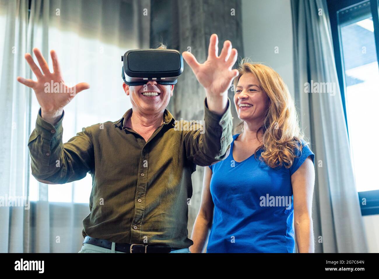 Mature married couple at home playing with virtual reality glasses ...