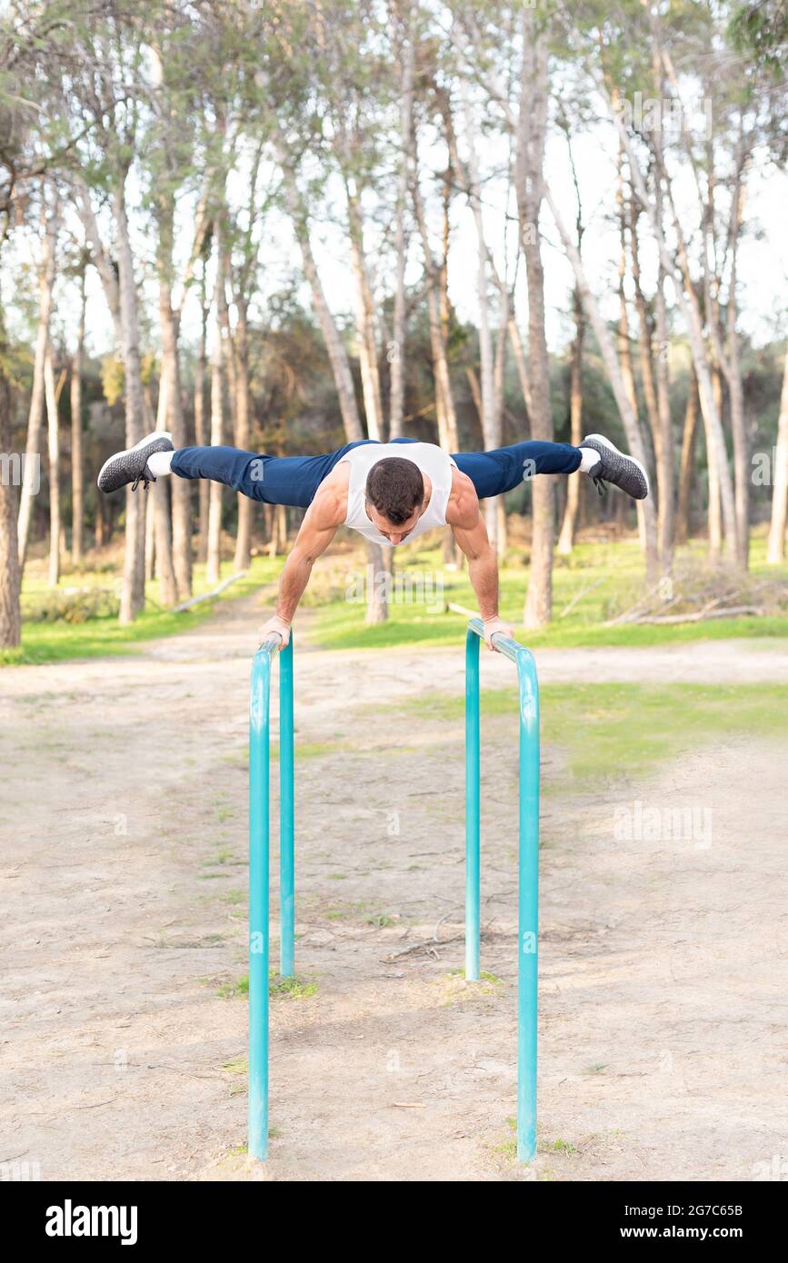 Male athlete exercising on parallel bars in forest Stock Photo - Alamy