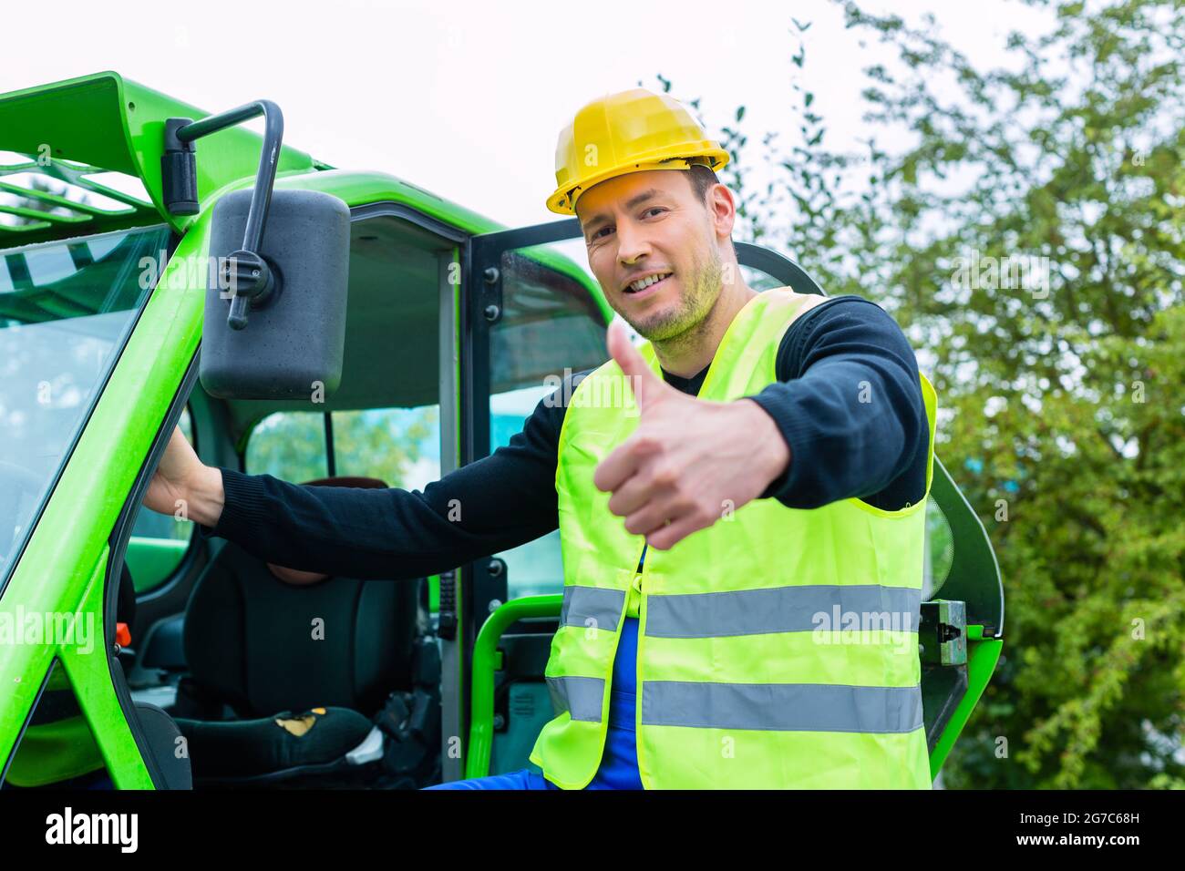 Builder or driver standing in front of construction machinery on ...