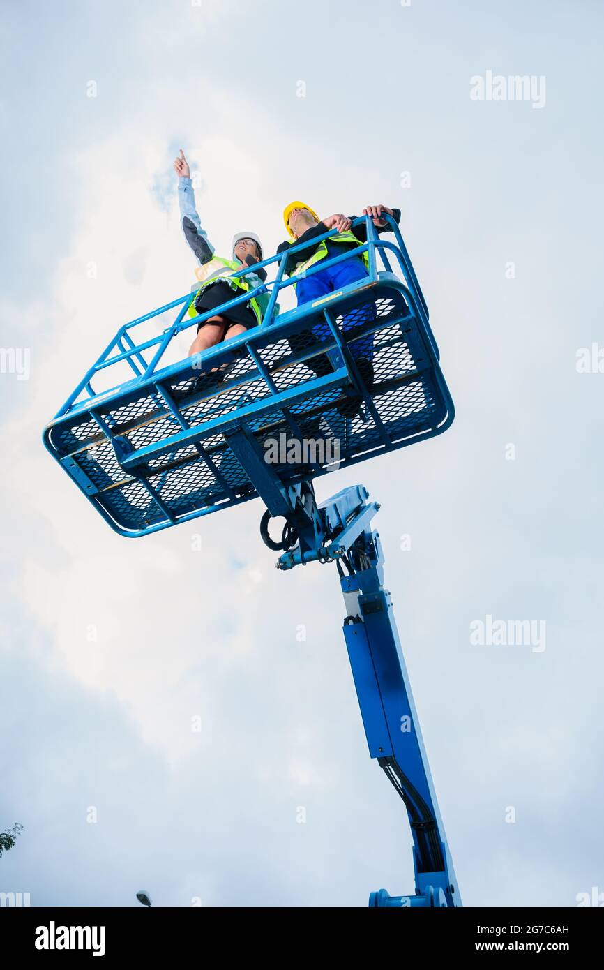 Construction workers on site in hydraulic lifting ramp discussing the ...