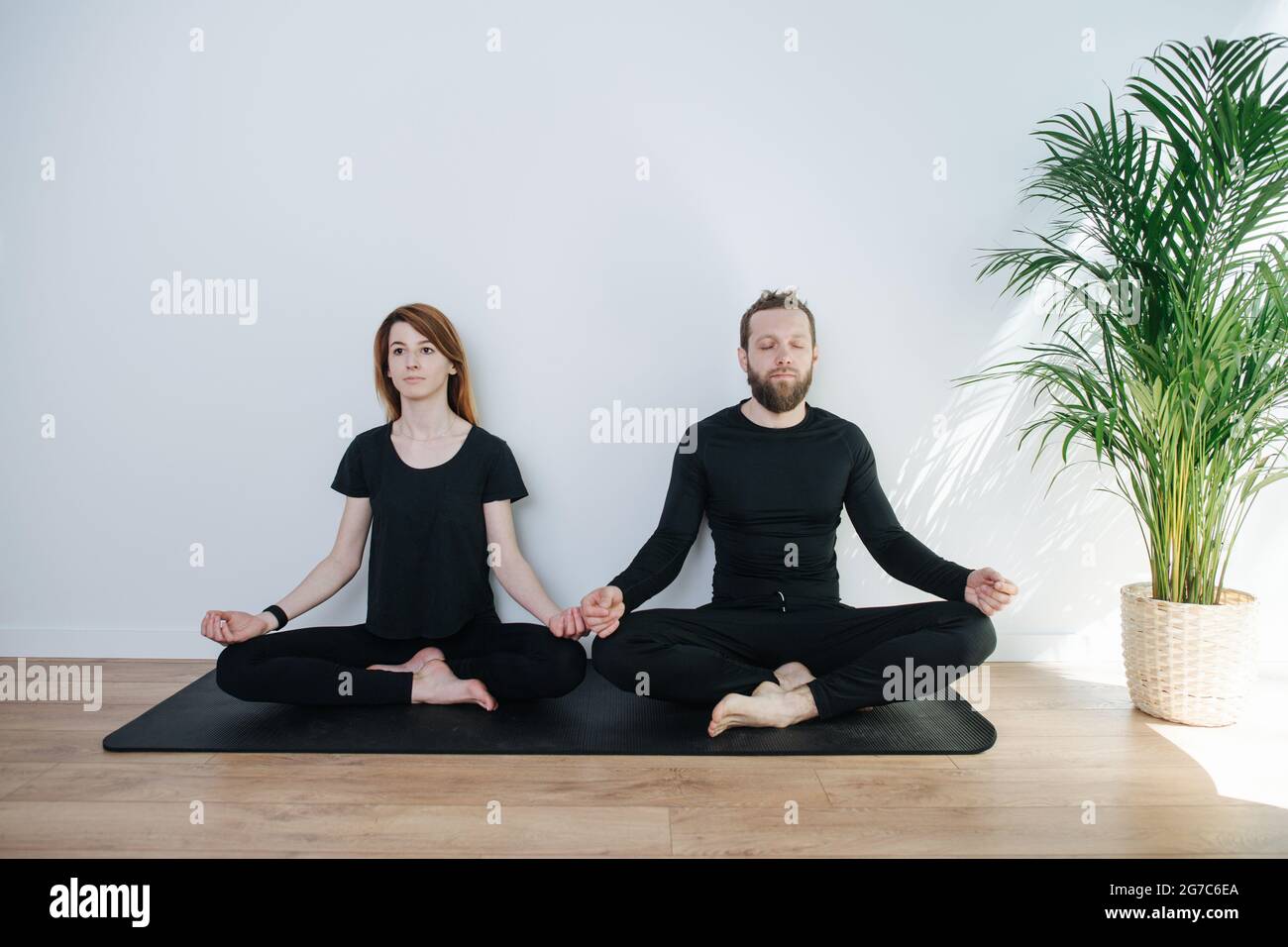 Relaxed couple meditating next to each other, sitting on a single mat ...