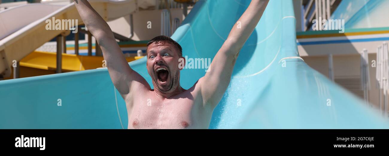Joyful man slides down slide in water park Stock Photo - Alamy