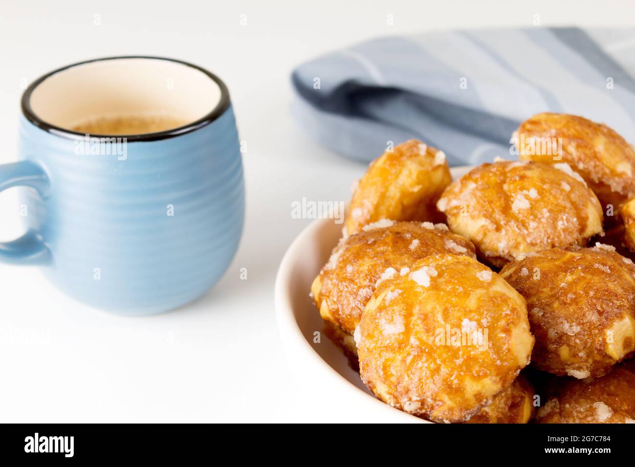 french chouquettes puffs with perles of sugar on plate with blue cup of ...
