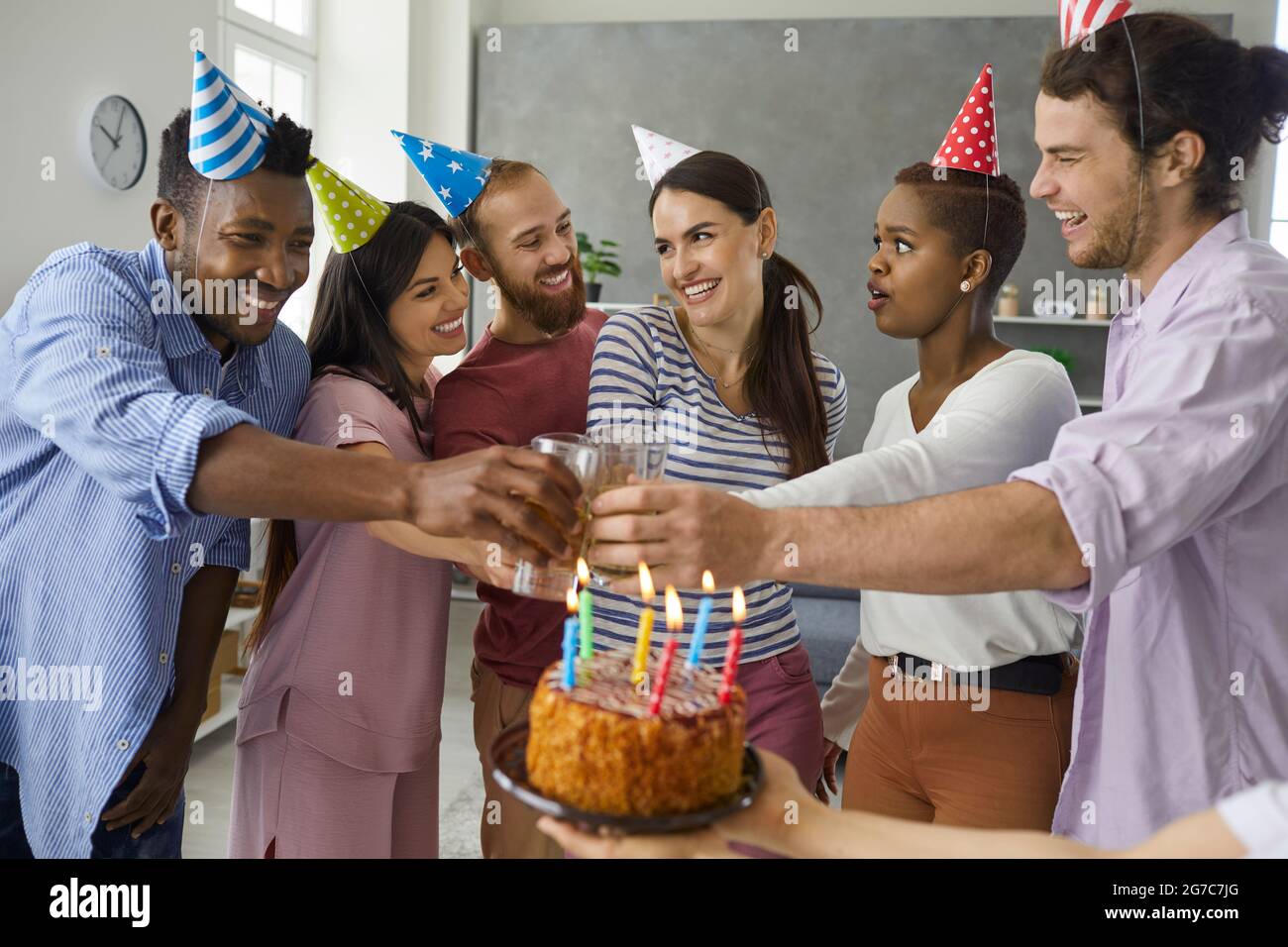 Group of multiracial people in conical party hats applaud while the ...