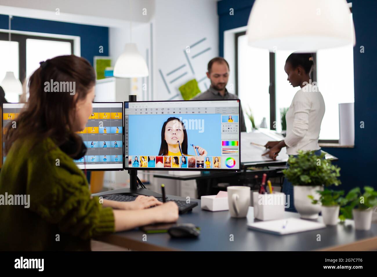 Female photographer edits photos in creative media agency office ...