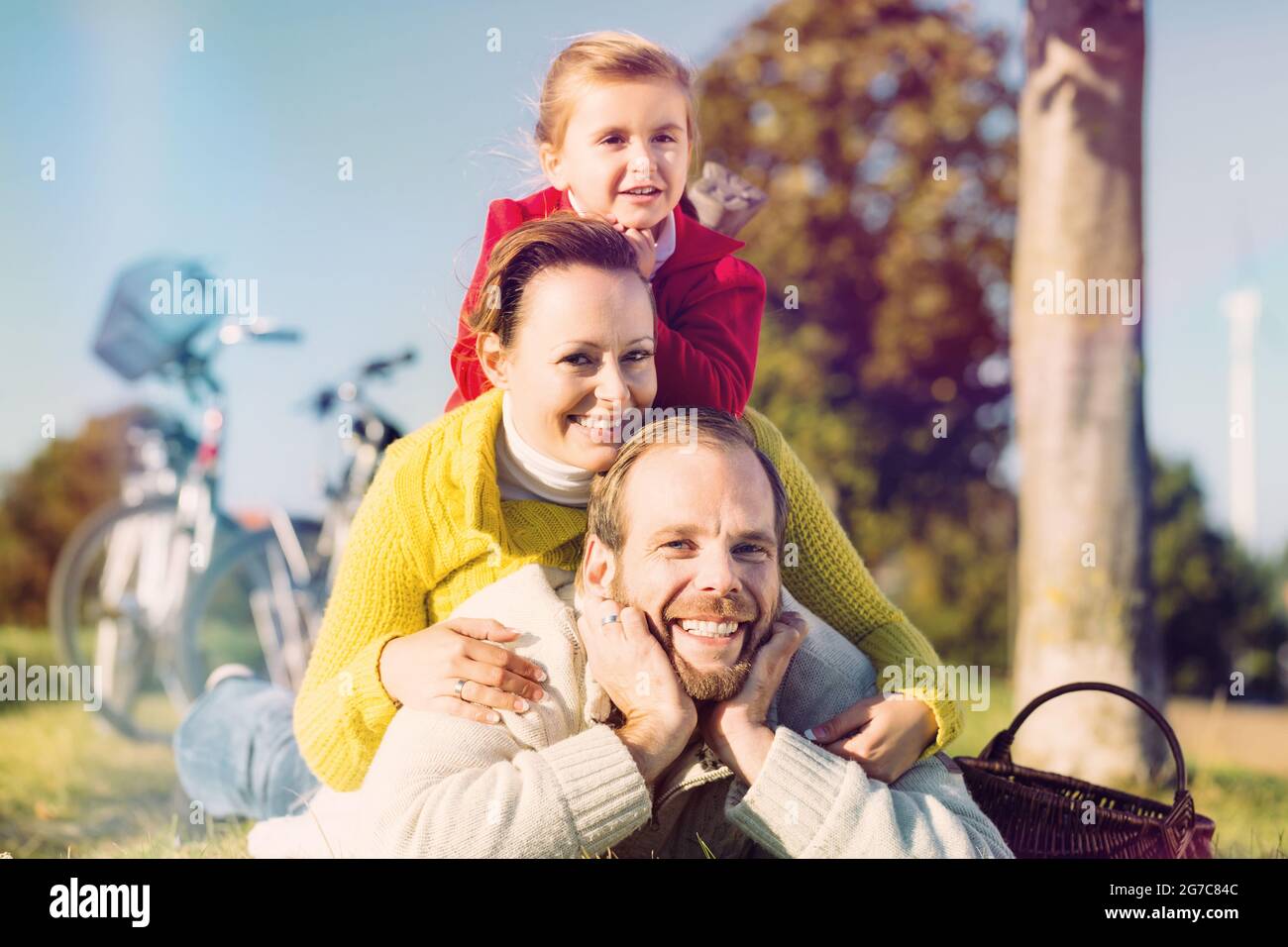 Family with mother, father and daughter having break on family trip with bicycle or cycle in ...