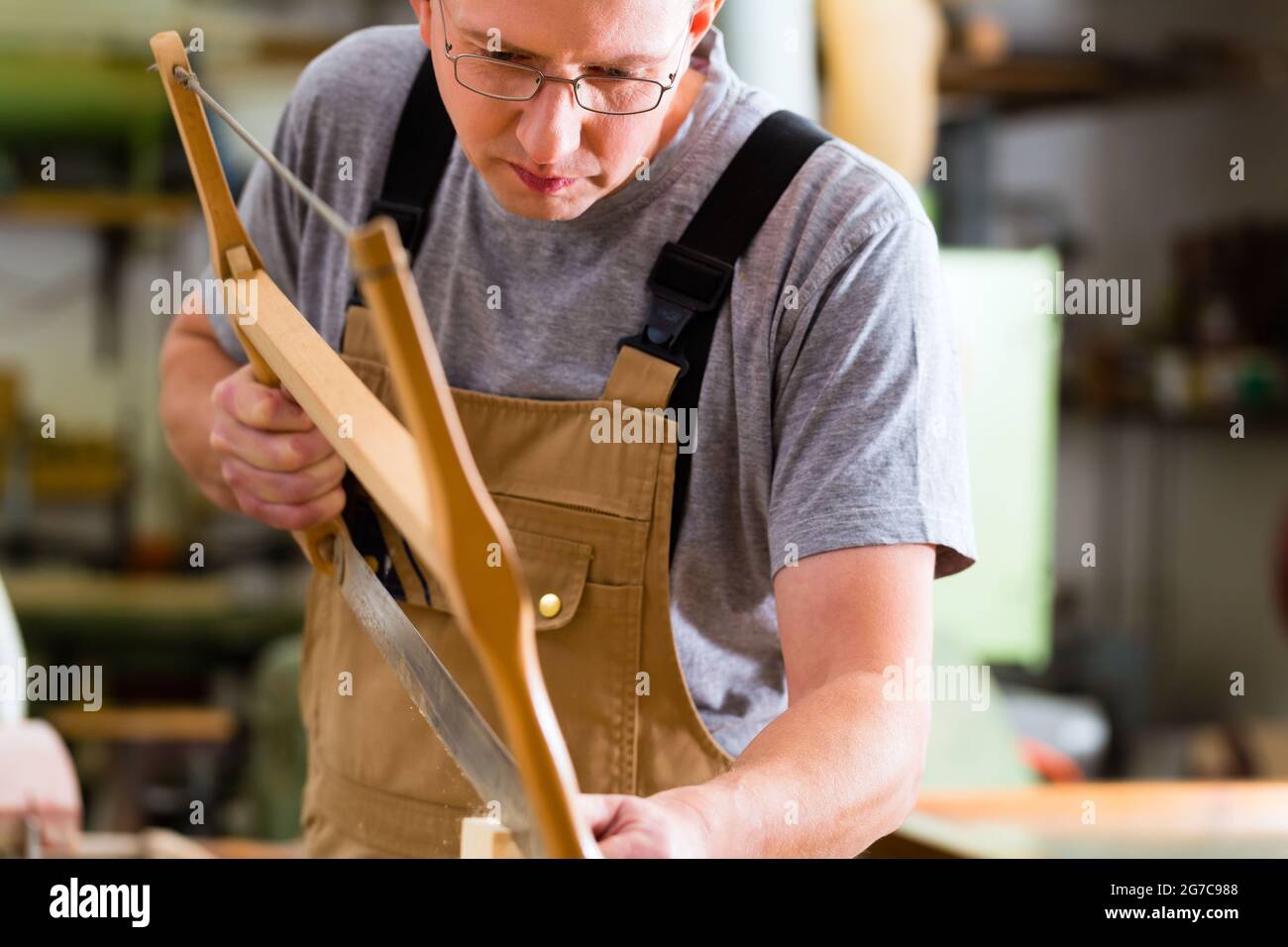 Carpenter working on a hand saw cutting a tenon in drawers in his ...