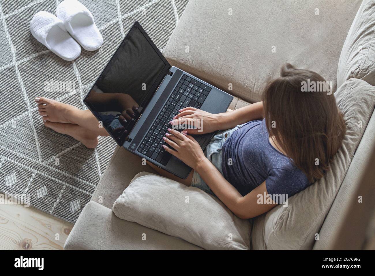 Young woman sitting on sofa and using laptop at home Stock Photo - Alamy