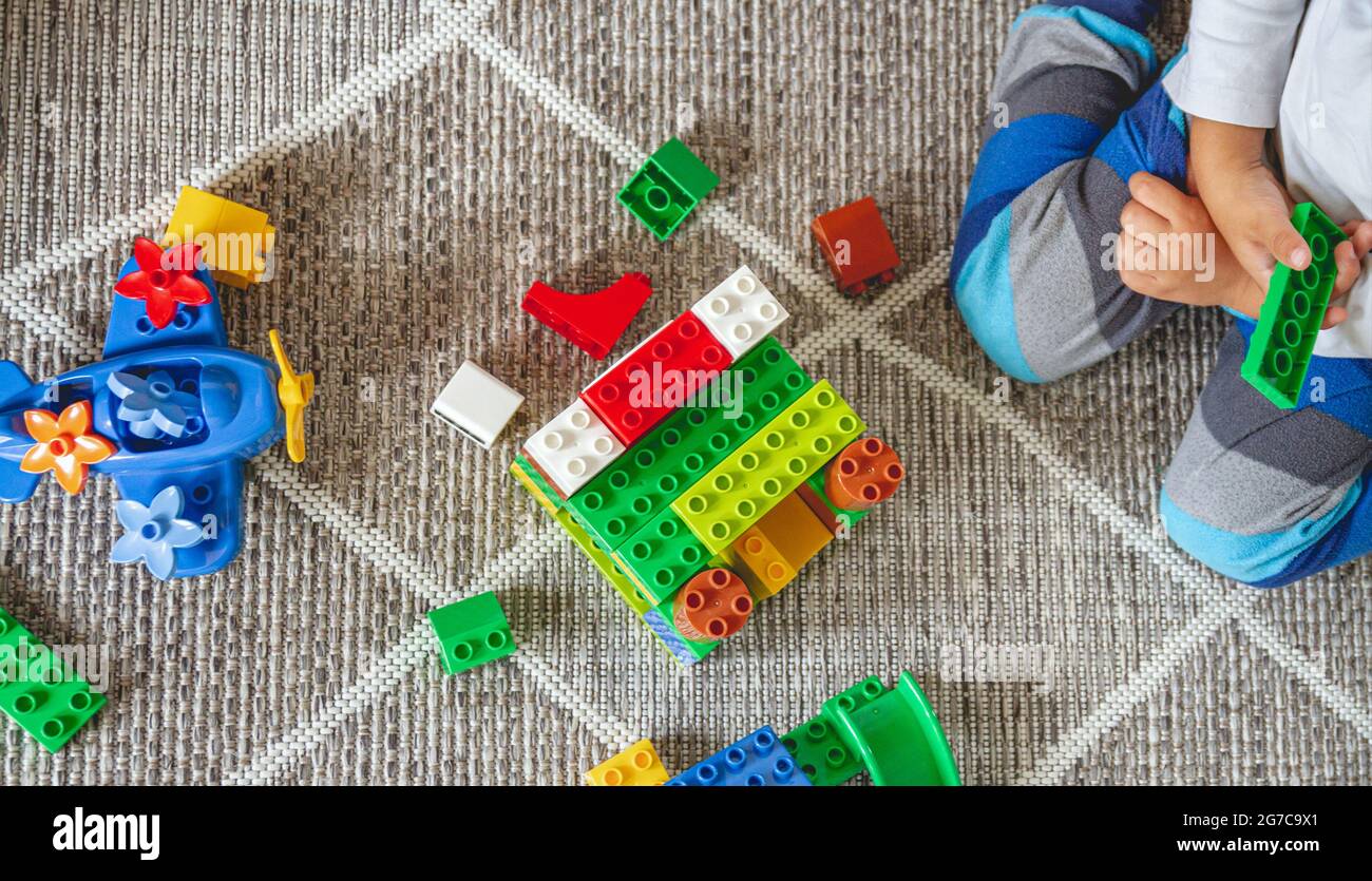 Child playing with toy blocks sitting on floor Stock Photo - Alamy