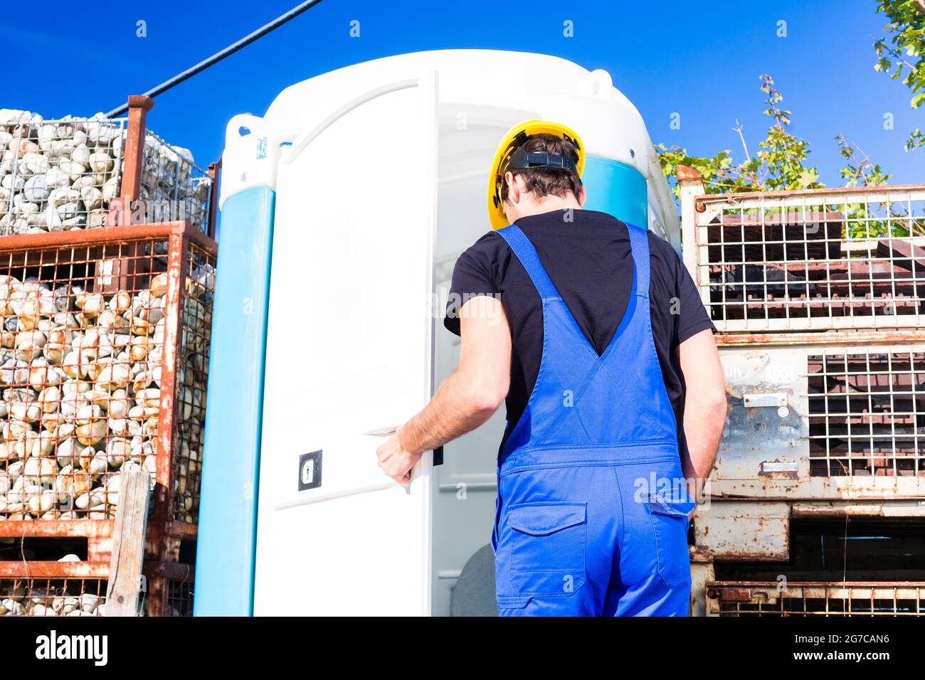 builder using mobile restroom or chemical toilet on construction or ...