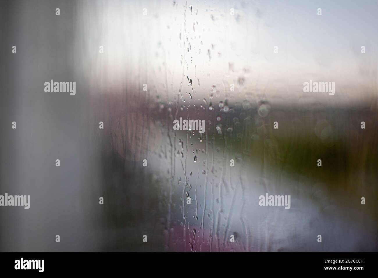 Rainy day through the window on cloudy grey sky and city buildings ...