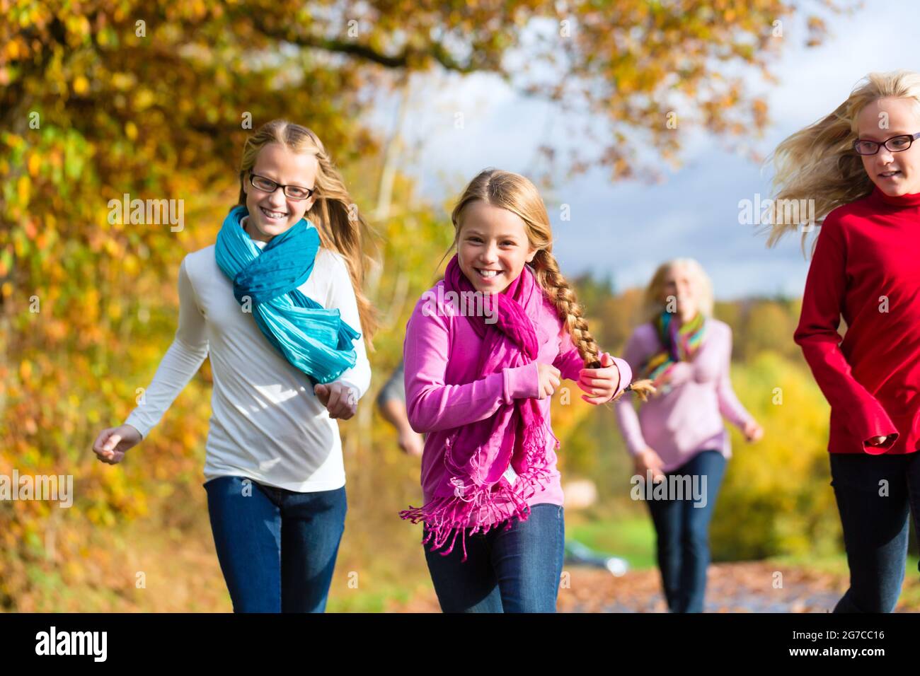 Girls running ahead at family walk through the park in fall or autumn ...