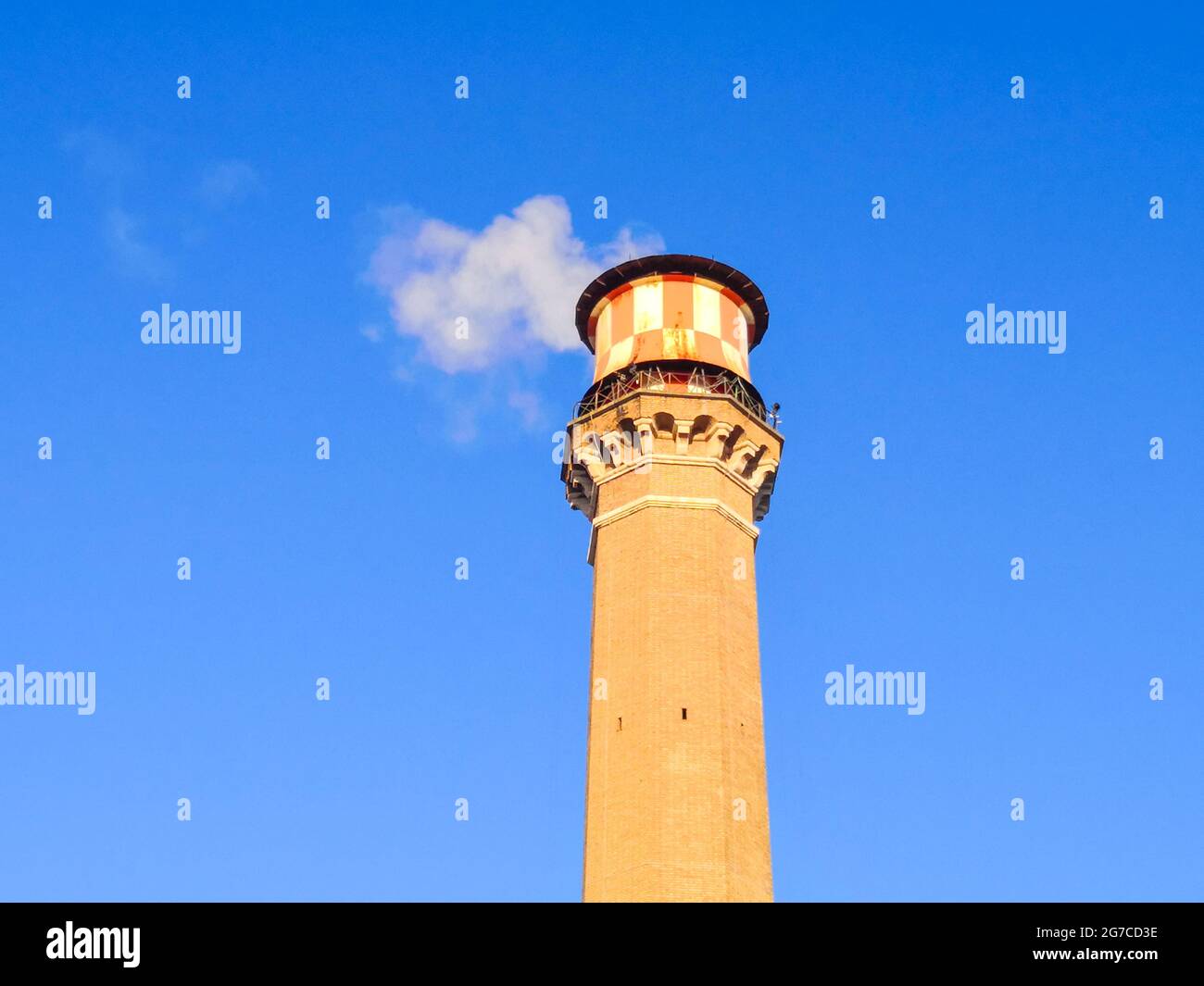 Tower made of bricks with a chimney from which white smoke comes out in ...