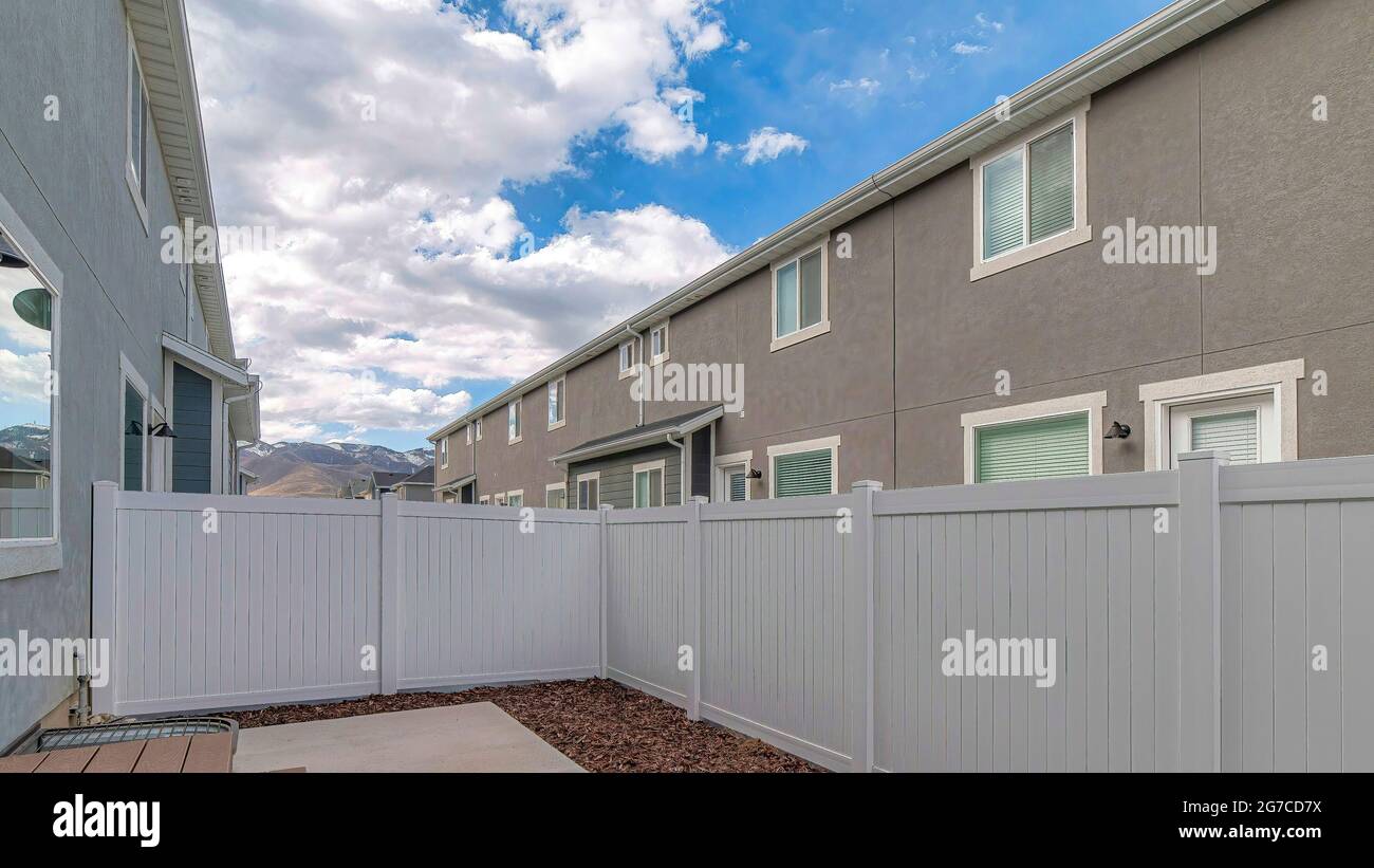 Pano Fully fenced backyard of two storey home with wooden steps leading ...
