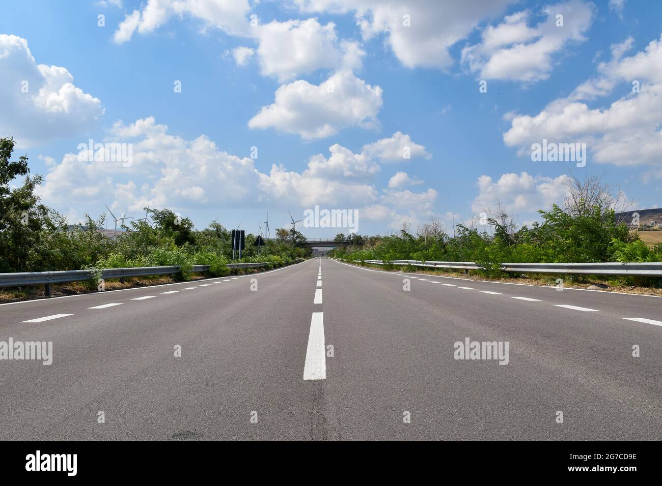 suburban road, or highway, seen in perspective under a blue sky with a ...