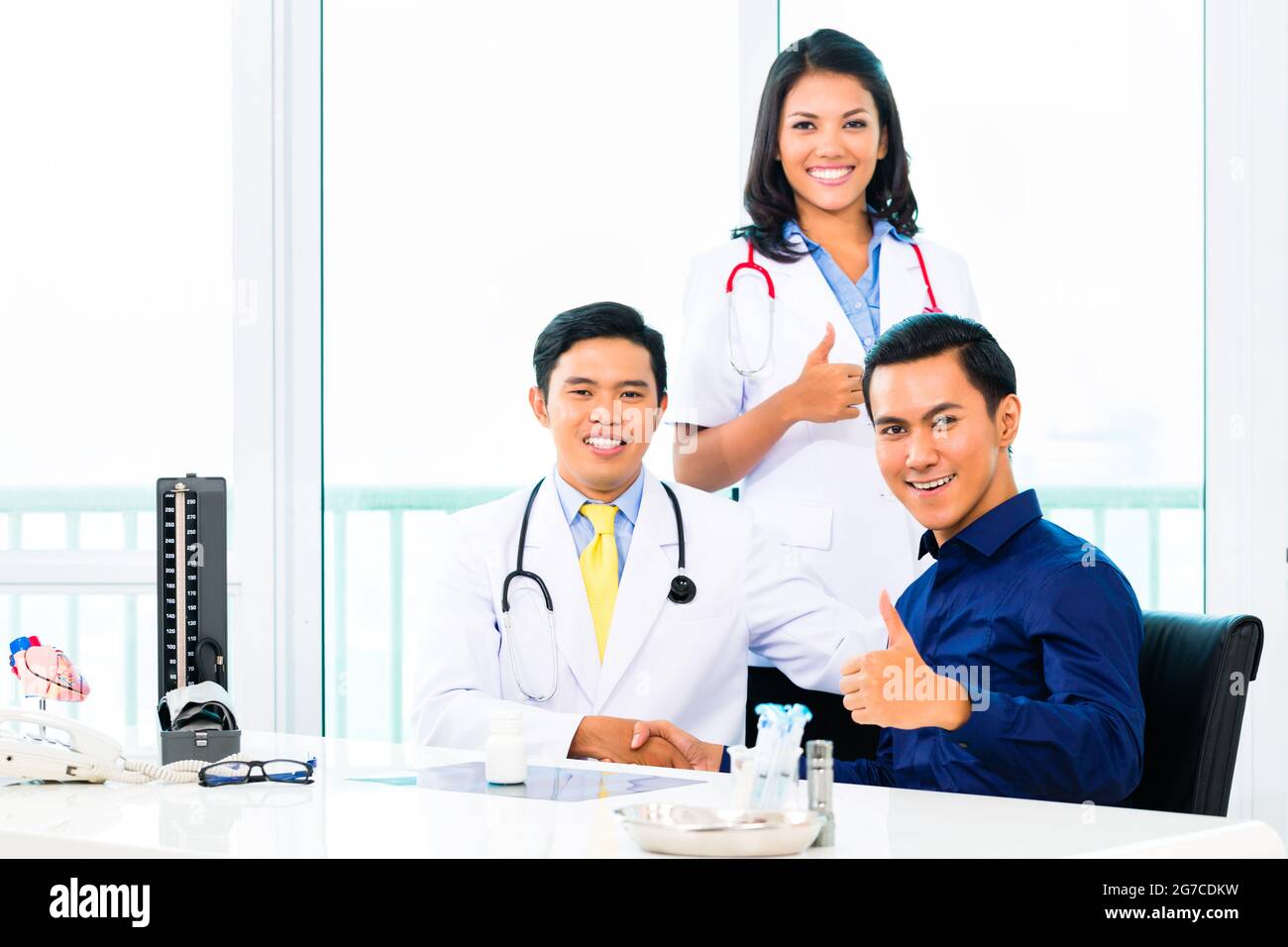 Asian doctor giving patient handshake for complete healing in practice ...