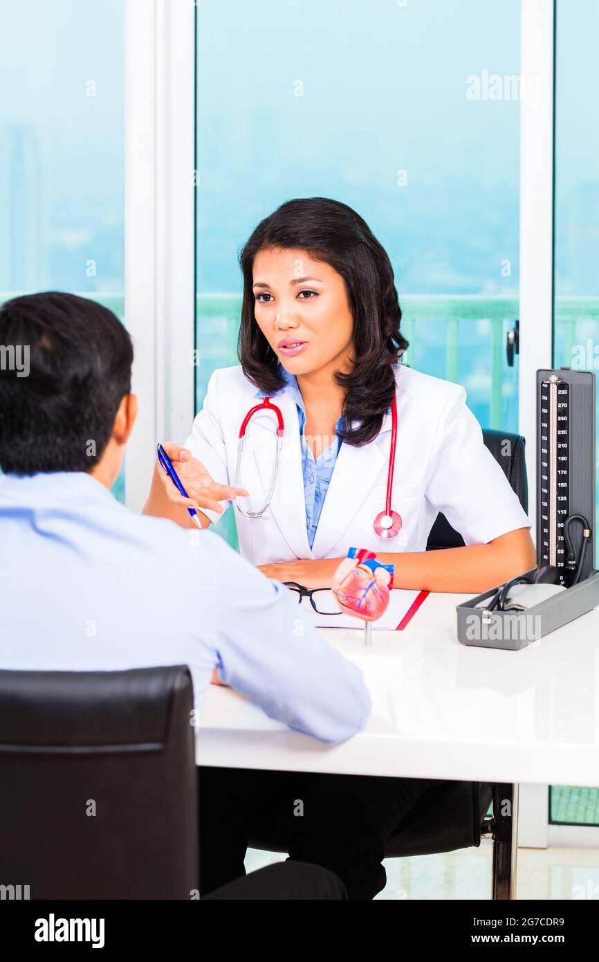 Asian female doctor giving patient medical advice in practice or office ...