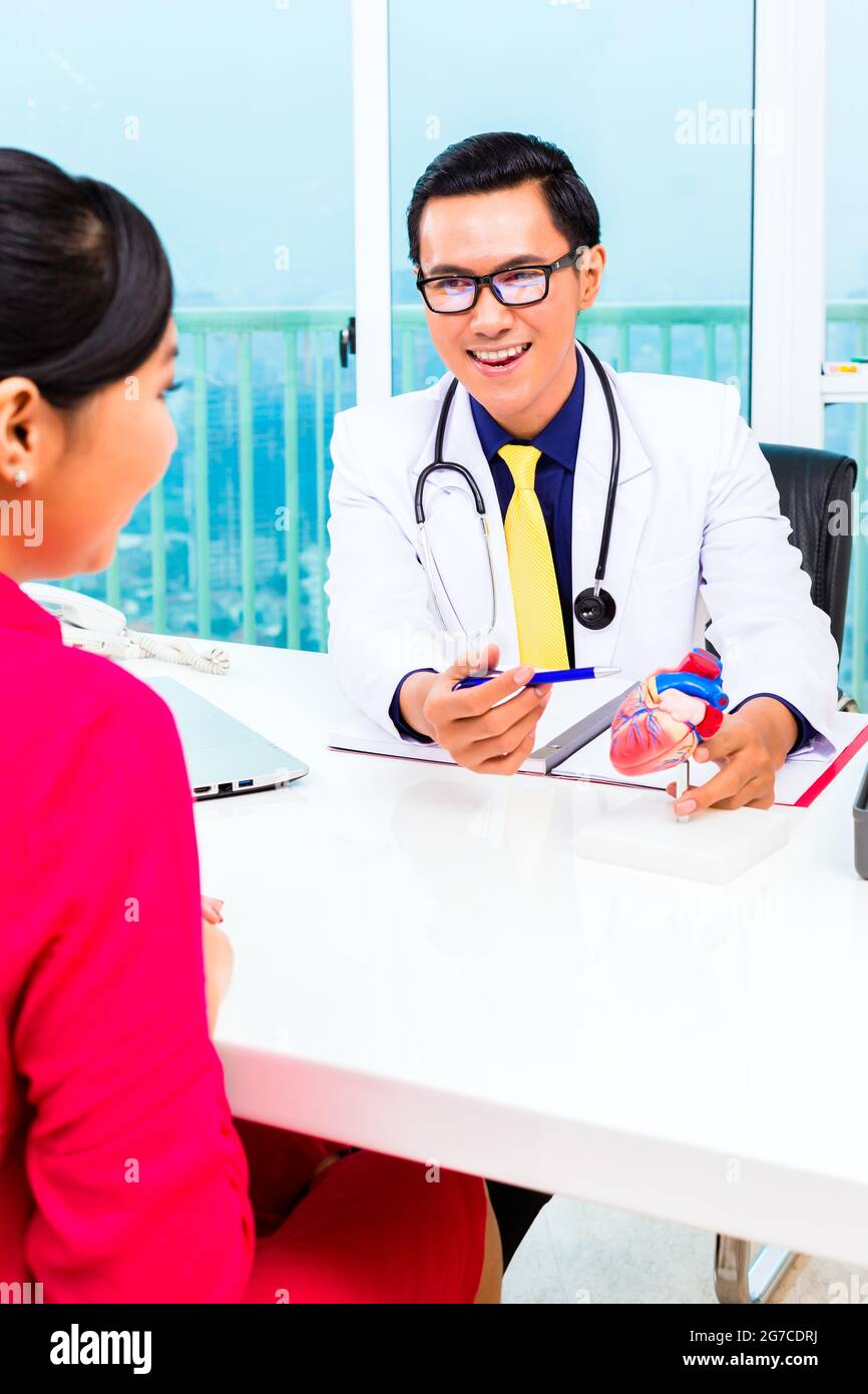 Asian doctor giving patient medical advice in practice or office Stock ...