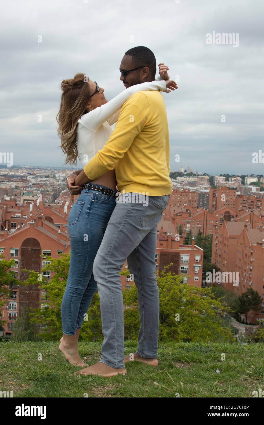 Young Interracial Couple Hugging Laughing And Kissing In A Park Stock