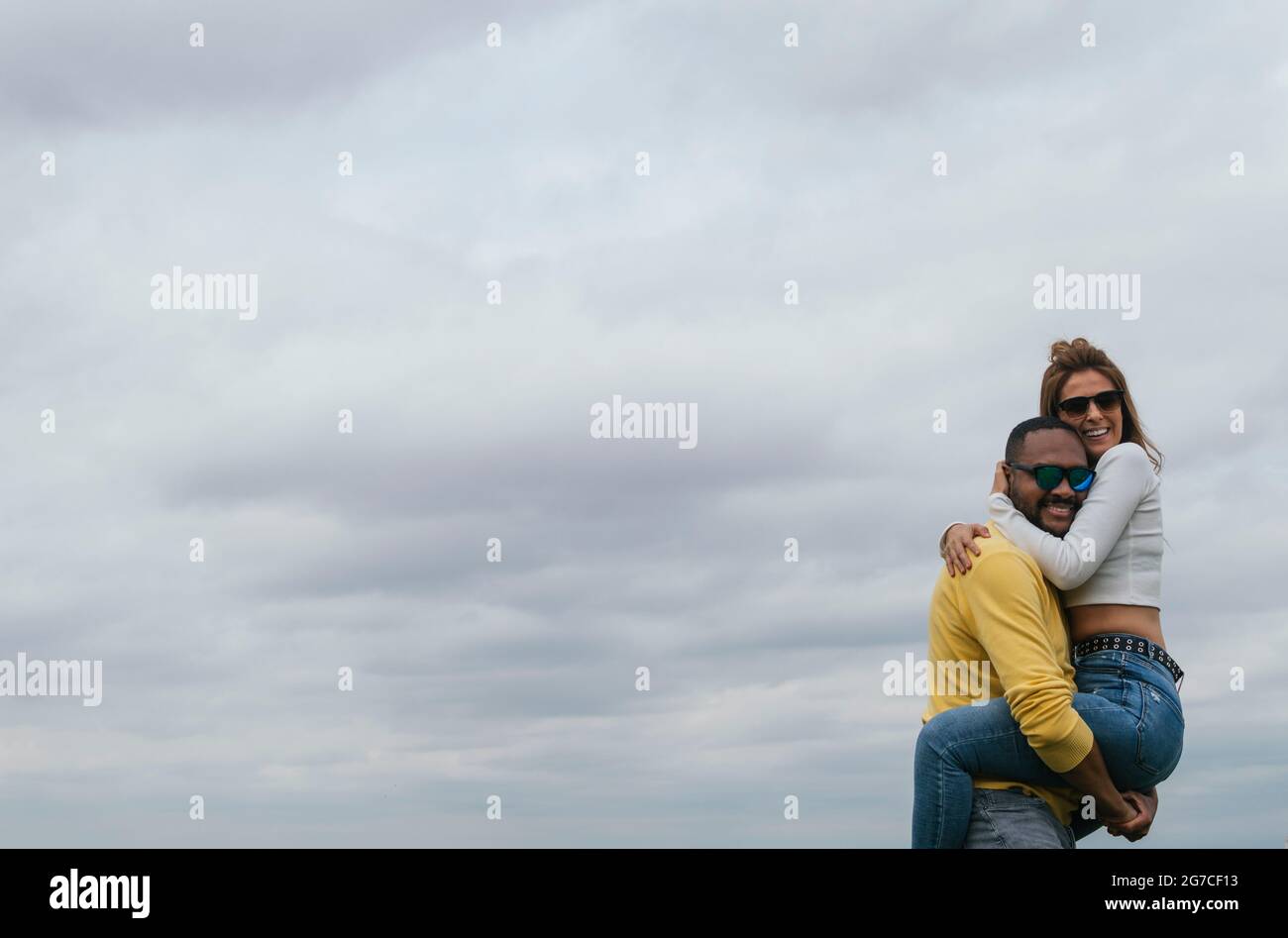 Young Interracial Couple Hugging Laughing And Kissing In A Park Stock