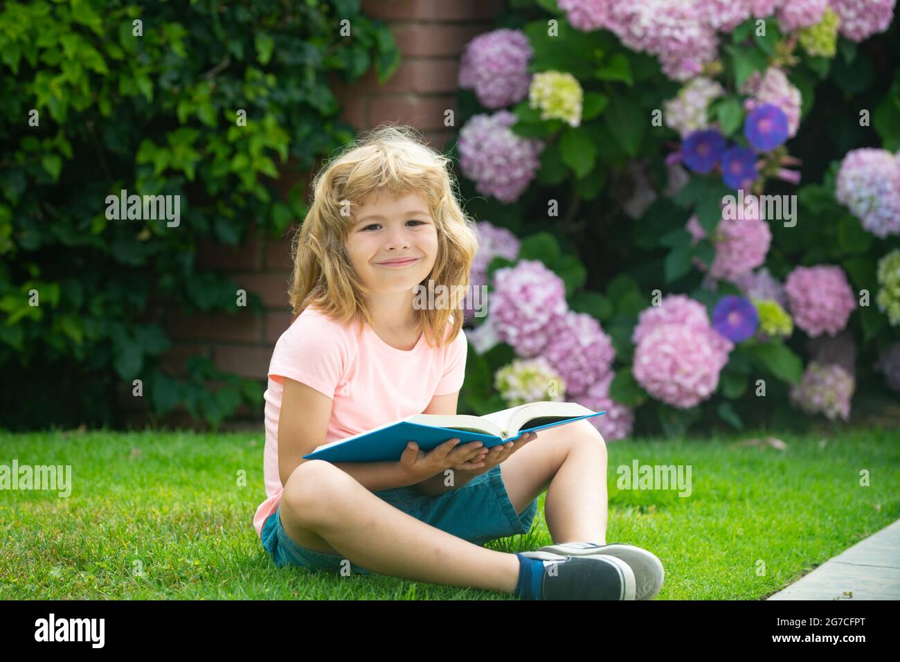 Child relax in the holiday. Kid read books on grass background ...