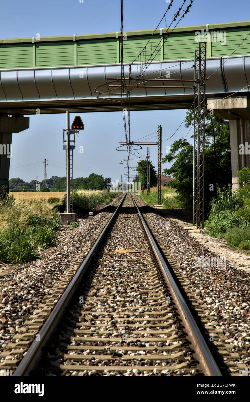 Railroad track passing under a viaduct in the italian countryside in ...