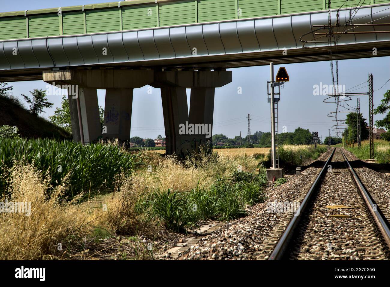 Railroad track passing under a viaduct in the italian countryside in ...