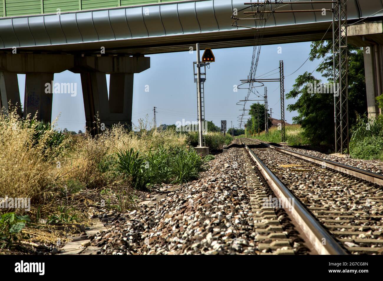 Railroad track passing under a viaduct in the italian countryside in ...