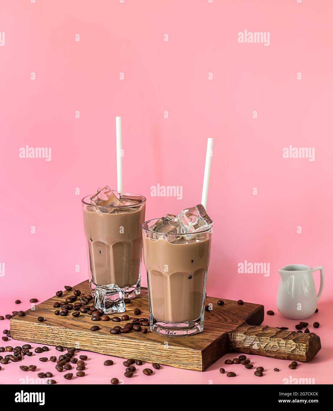 Cold brew coffee with ice cubes and milk, light pink background ...