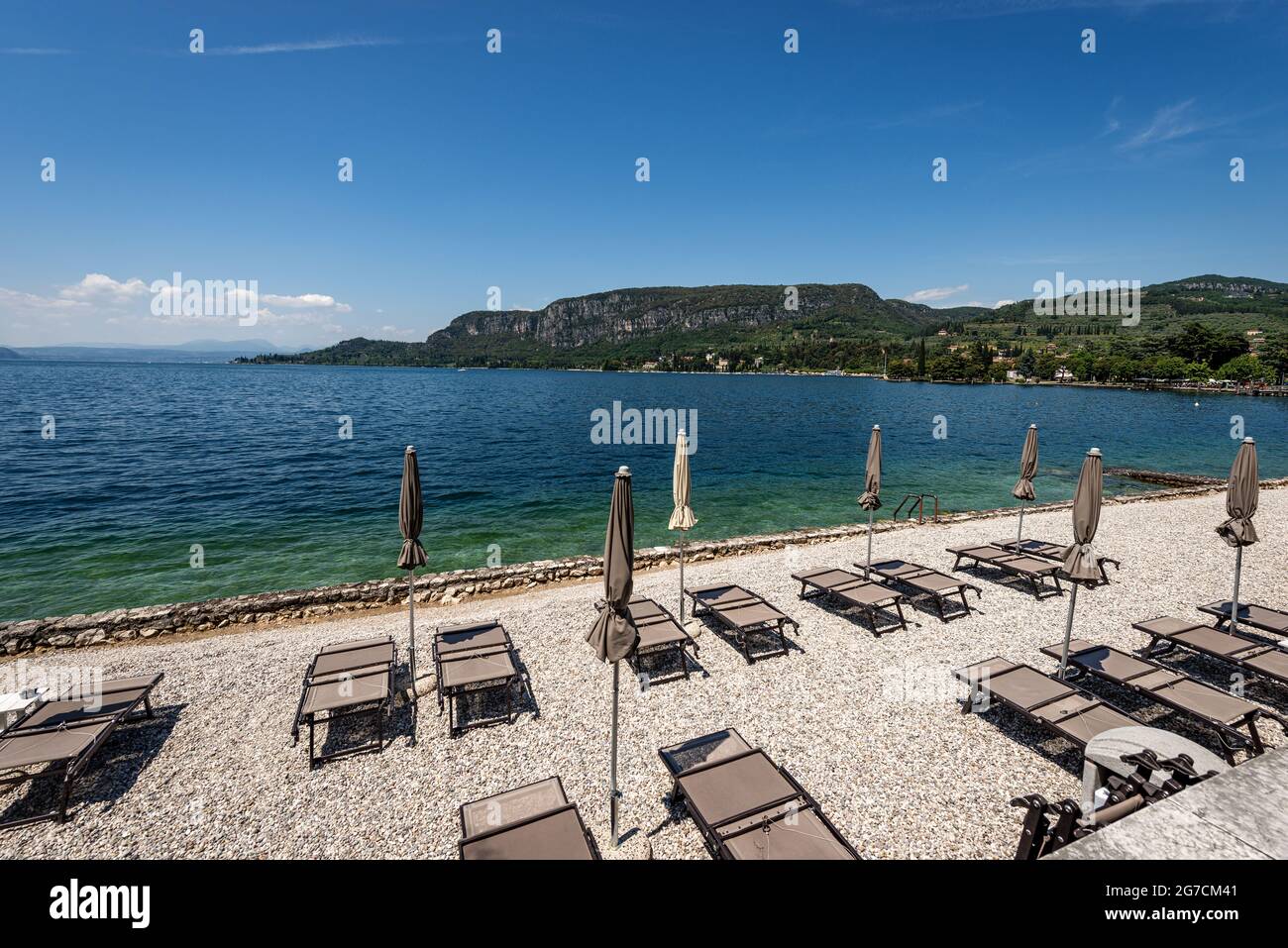 Beach Umbrellas and Empty Deck Chairs on a beauty beach on Lake Garda ...