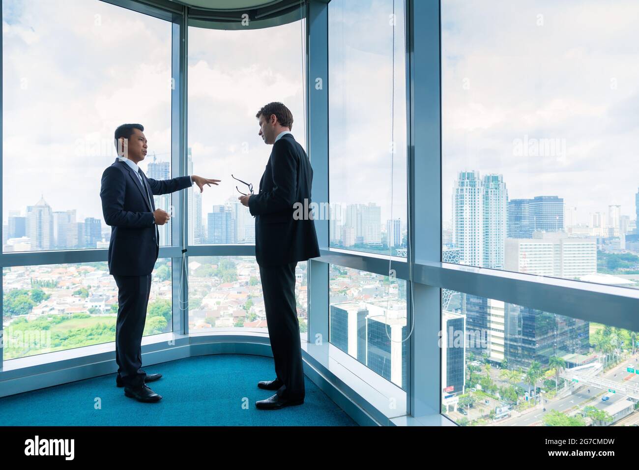 Businessmen standing in front of window and talking Stock Photo - Alamy
