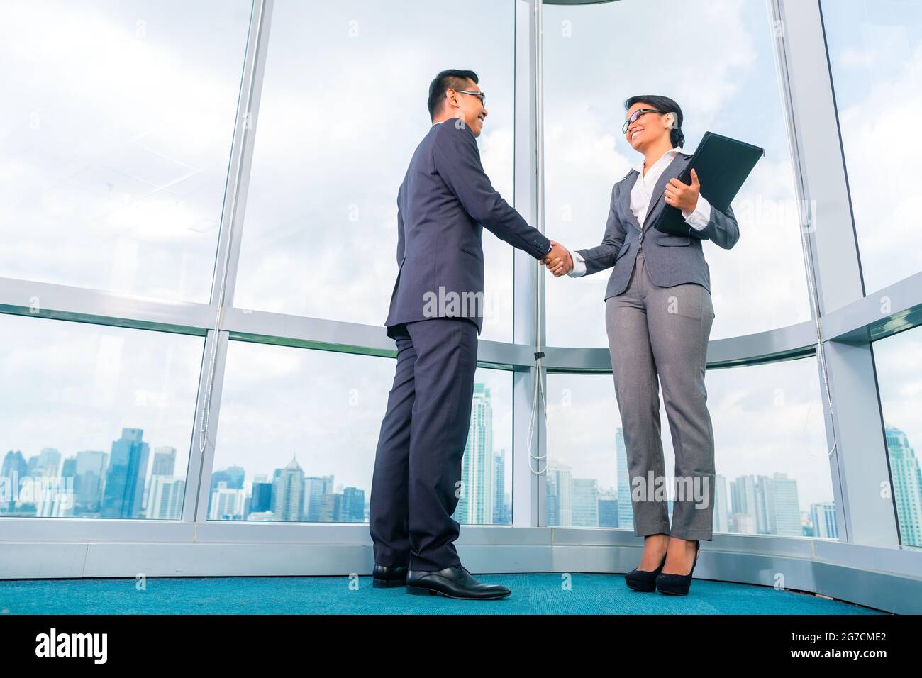 Low angle view of Asian business partners shaking hands Stock Photo - Alamy