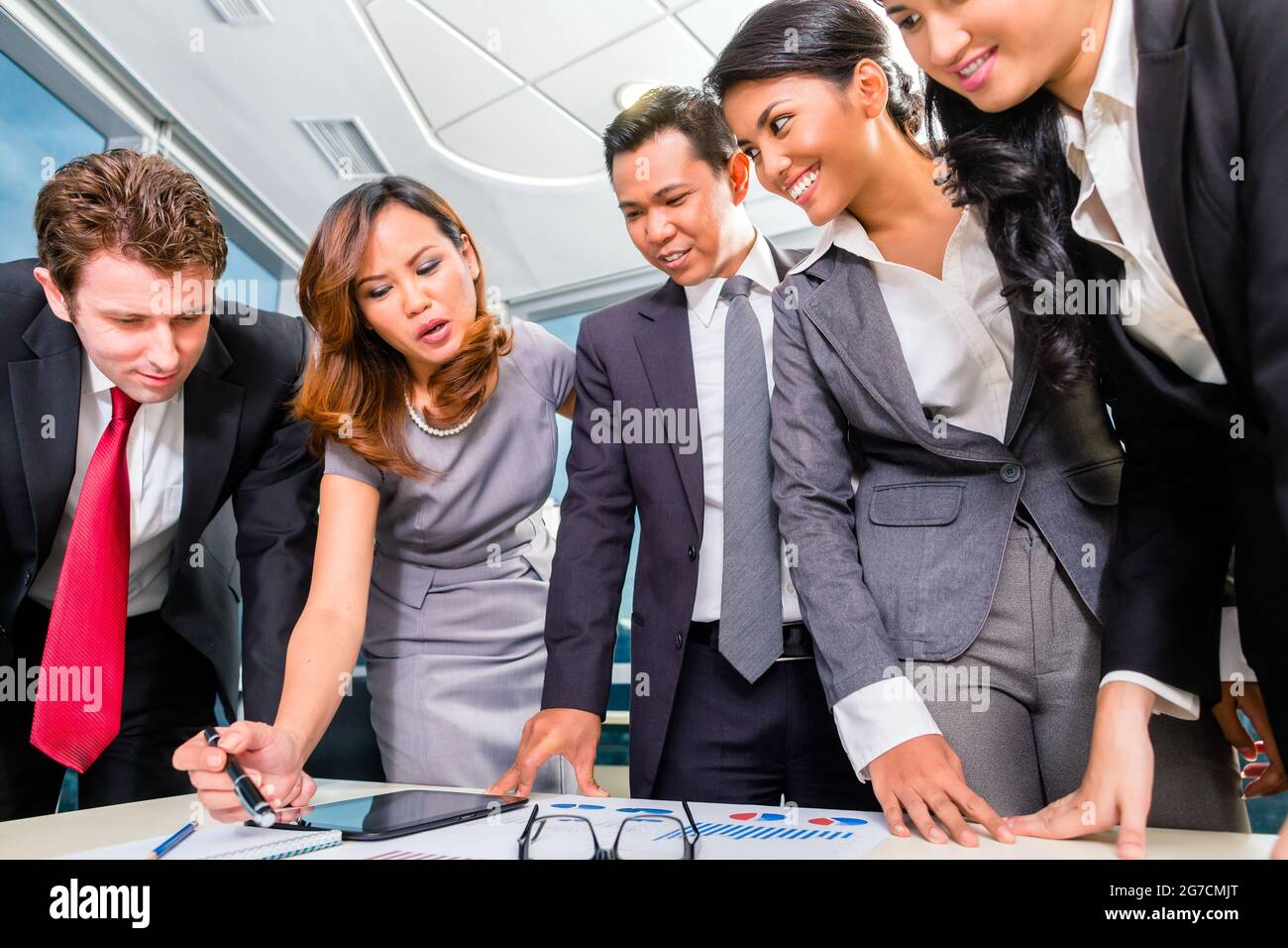 Asian Businesspeople standing around a table Stock Photo - Alamy