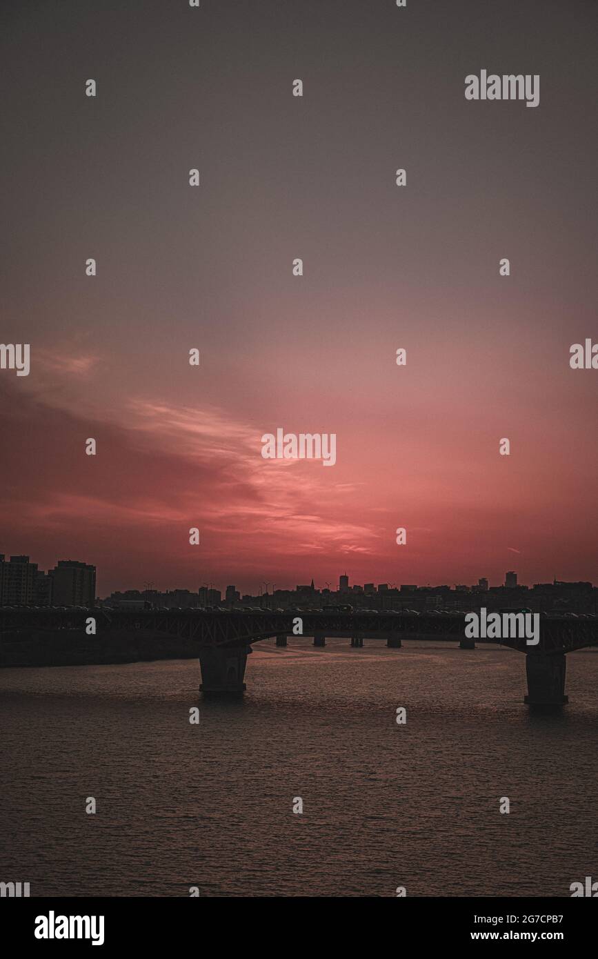 Bridge over the river under the beautiful sunset sky with city ...