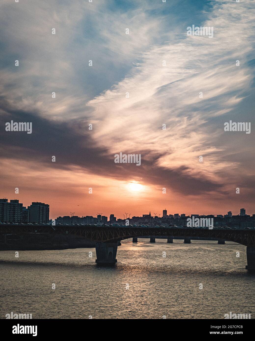 Bridge over the river under sunset sky with city buildings in the ...
