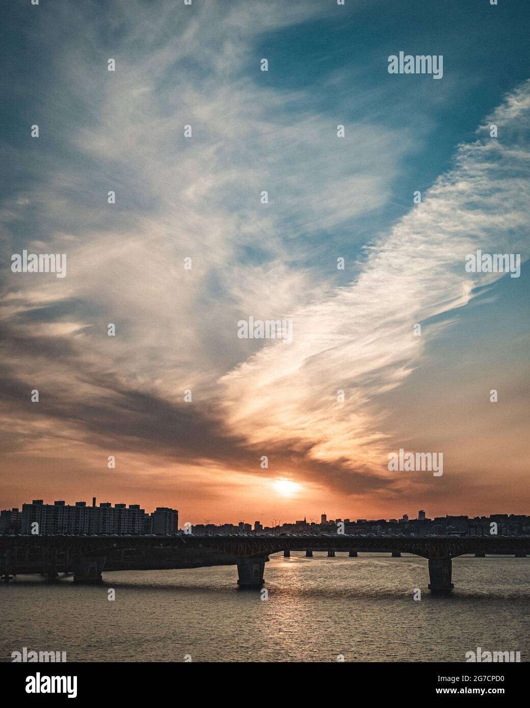 Bridge over the river under sunset sky with city buildings in the ...