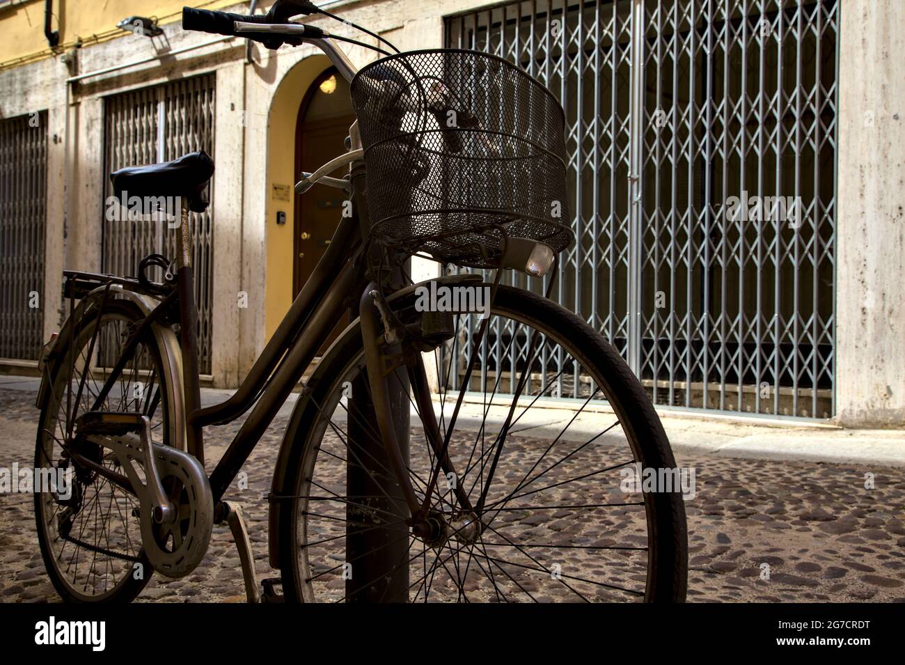 Bike in a shady street with closed shops Stock Photo - Alamy