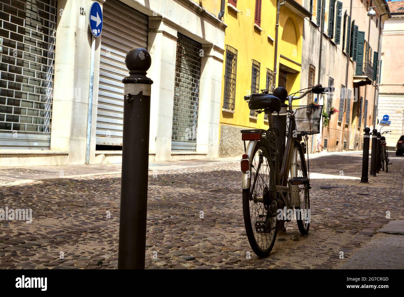 Bike in a shady street with closed shops Stock Photo - Alamy